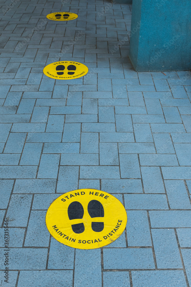 Social distancing sign stickers plastered on a brick floor near the ...