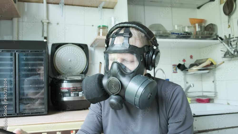 Wideo Stock: funny man in gas mask listens to music in headphones ...
