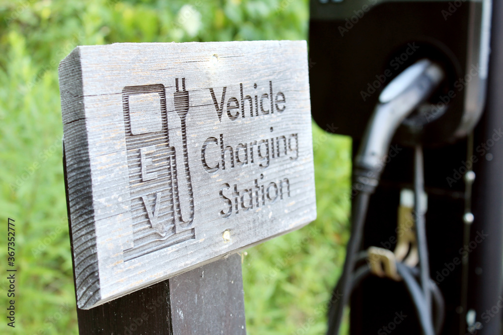 Wooden sign for electric vehicle charging with trees and the charging ...