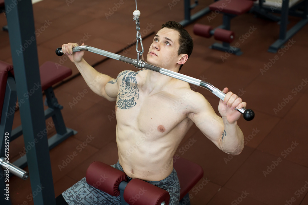 .Shoulder pull down machine. Fitness man working out lat pulldown ...