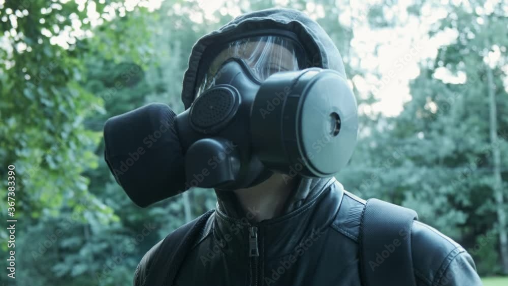 man in gas mask, black leather jacket with hood standing outdoors at ...