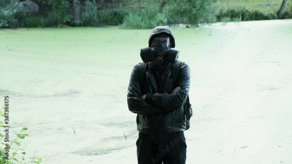man in gas mask, leather jacket with hood turns around near toxic ...