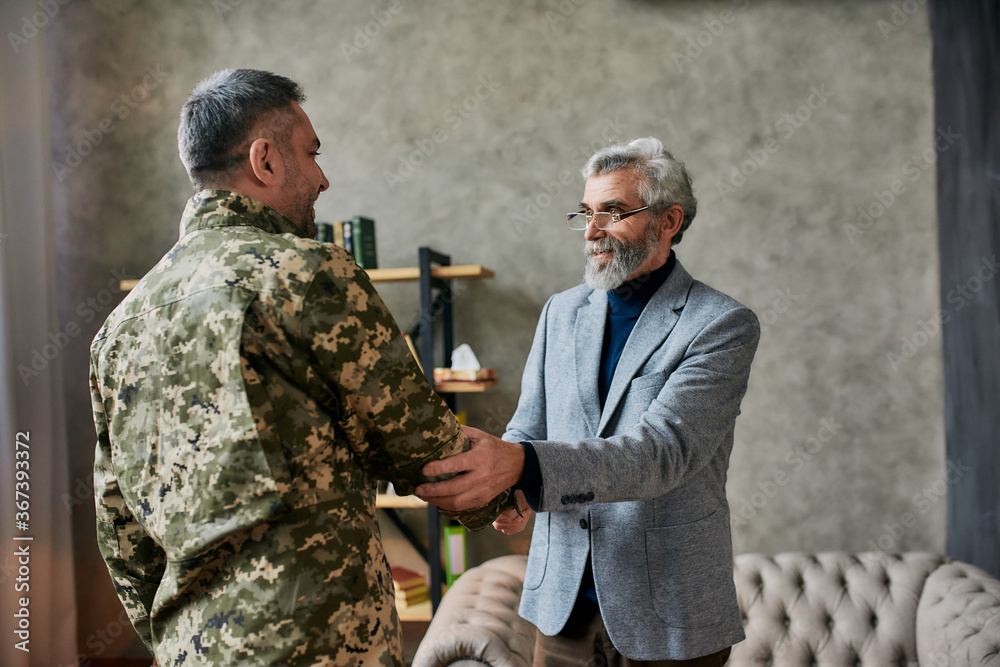 Real help. Mature psychologist smiling, shaking hands with middle aged ...