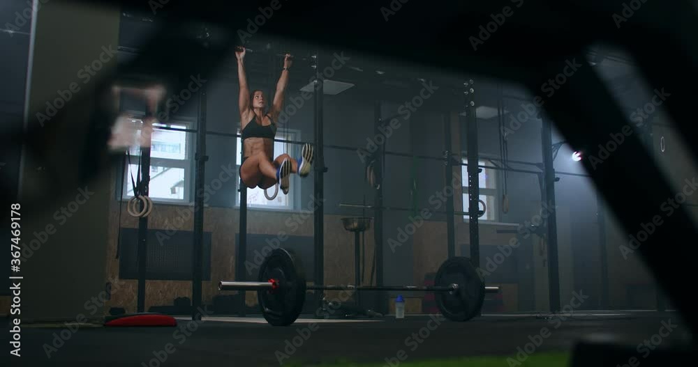 Slow motion: Raising feet up to bar on gym bar, attractive muscle woman exercise and train in ...