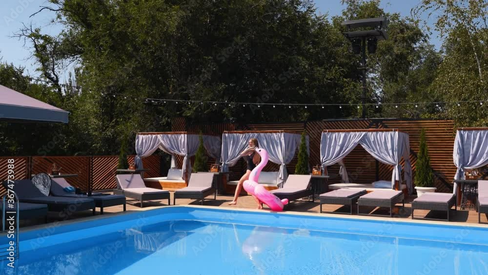 Hot pretty girl in bikini running with pink inflatable flamingo in hand ...