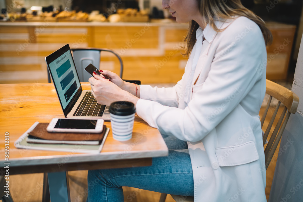 Side view of cropped female user holding credit debit card reading cvv ...