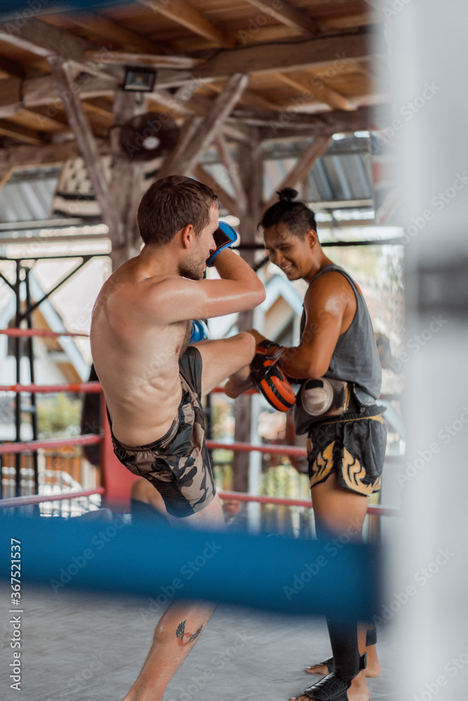 Training in the gym in the ring with a muay thai trainer. Tattooed ...