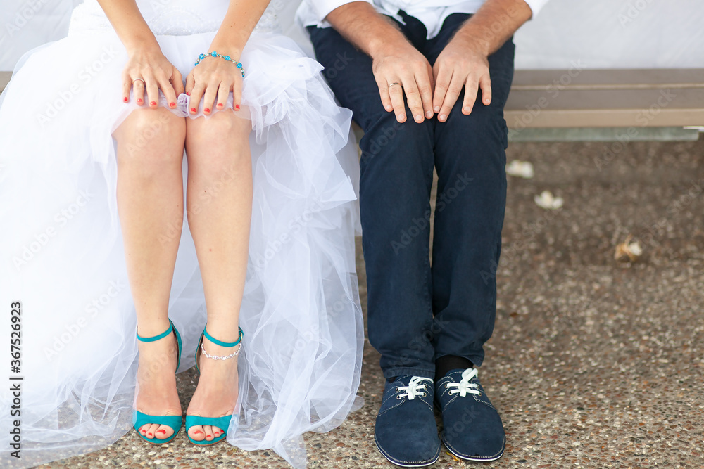legs of the bride in a white dress and the groom sitting on the bench ...