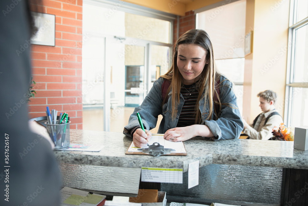 High school girl student filling out paper in school office Stock Photo ...