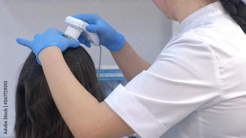 Doctor trichologist examines woman patient's hairs using trichoscope in ...
