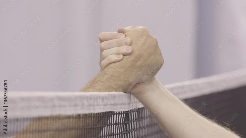 Close-up of two male Caucasian hands shaking over badminton or tennis ...
