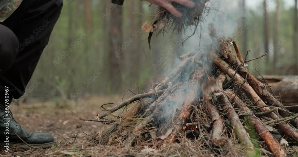 Low angle shot of a man is trying make a fire in the forest. Close-up ...