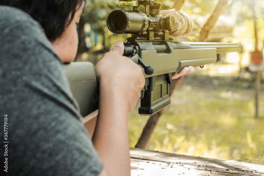 Military sniper with his precising sniper rifle aiming through scope ...