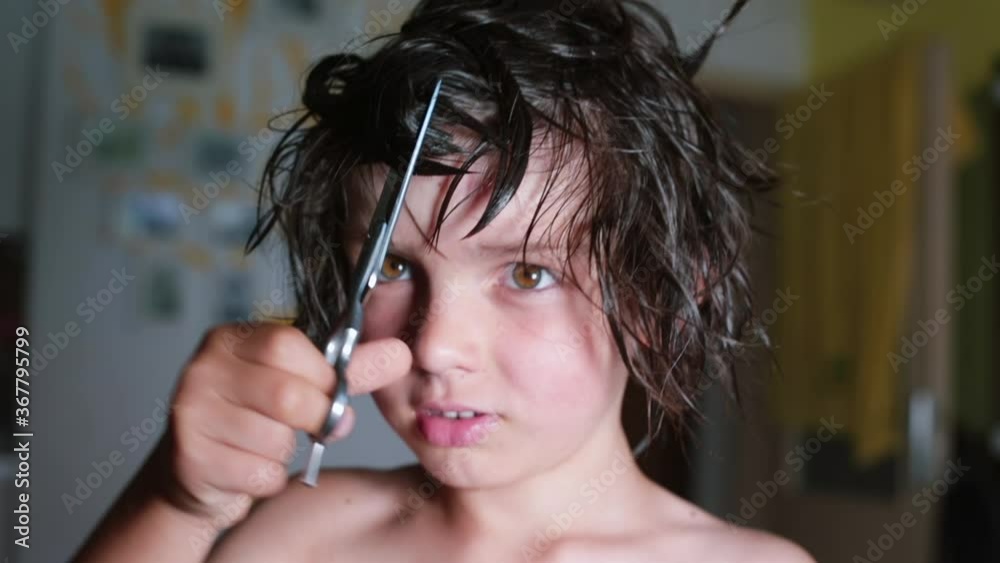 The boy cuts off his own hair with scissors. Do a haircut in self ...