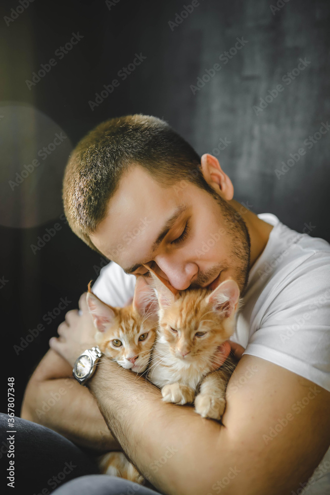 Handsome young man with a beard hugging red-headed maine coon cat. guy ...