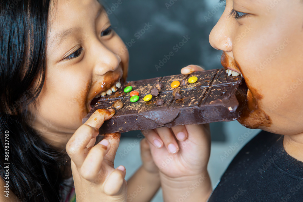 Two greedy kids biting a bar of chocolate Stock Photo | Adobe Stock