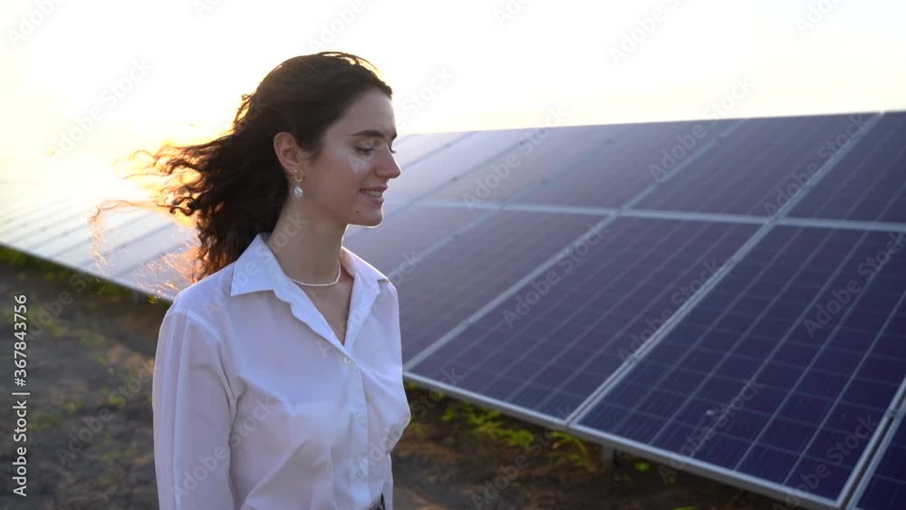 Wideo Stock: Woman walks near solar panels row on the ground at sunset ...