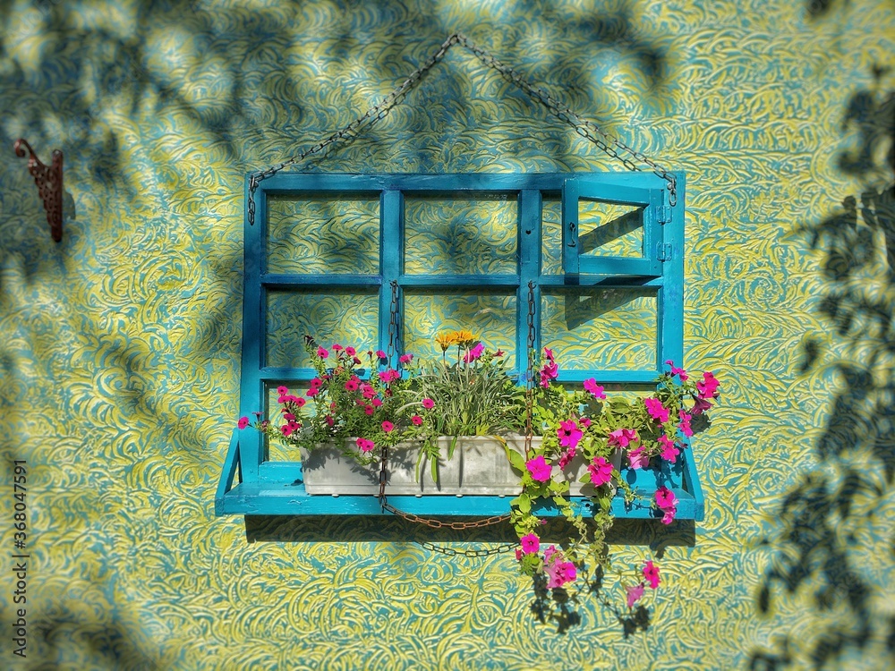 Decorative window with flowers hanging right on the wall of the house ...