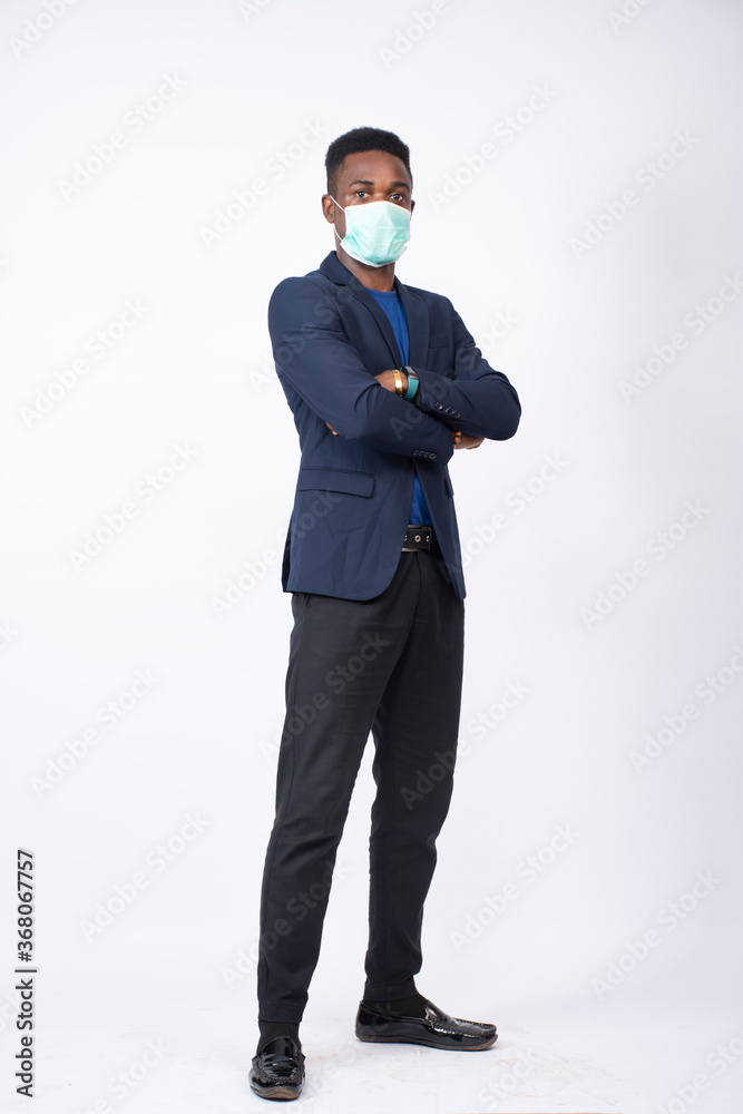 a young black man wearing a suit and face mask standing confidently ...