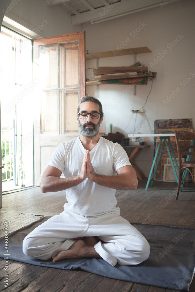 Man doing a yoga pose with his hands together as praying in a wooden ...