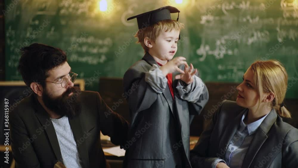 Funny little boy in graduation cap stands near a school board with ...