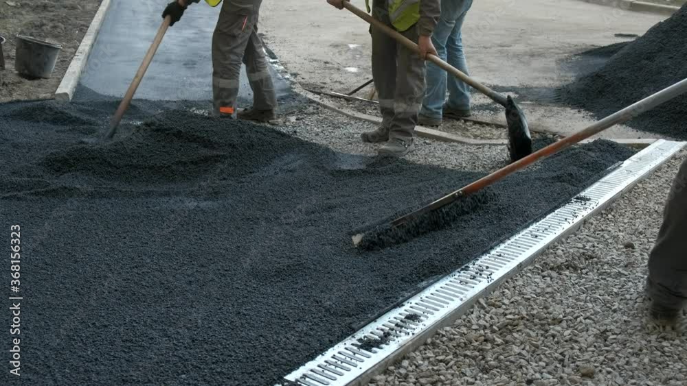 Workers pour asphalt with a shovel . Loosening and leveling of heated ...