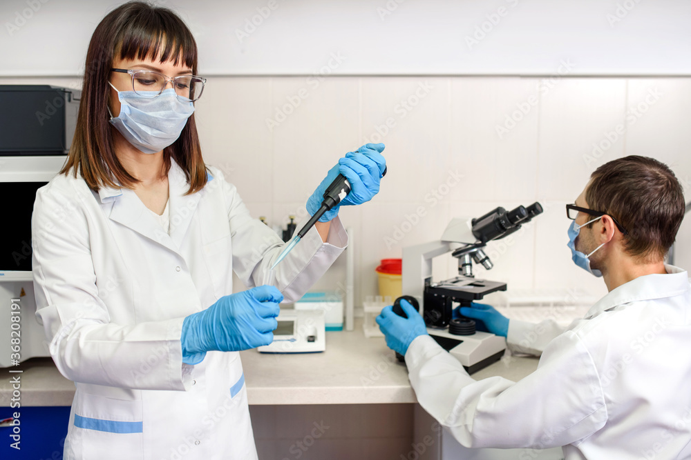 In the hospital laboratories working process, a young woman doctor is ...