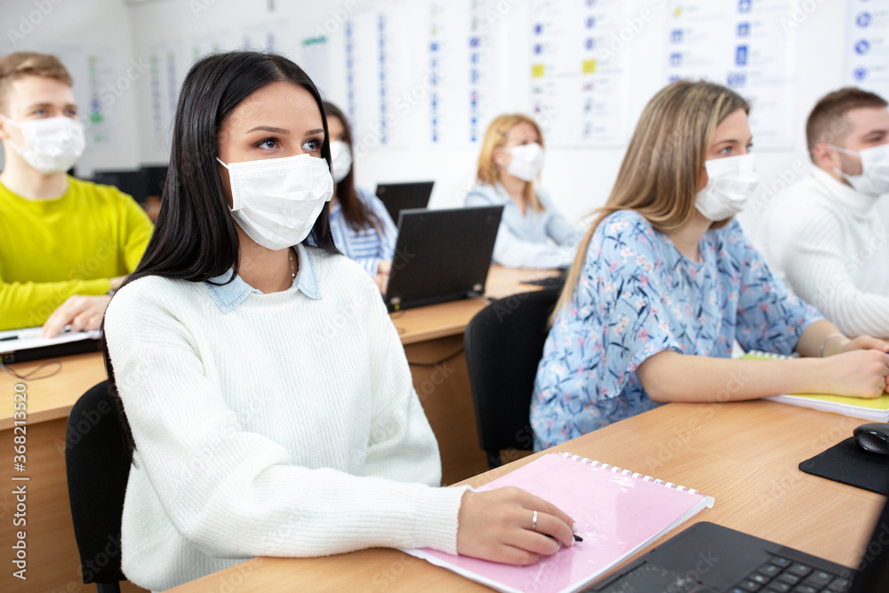 Students with safety and protection masks sitting in the classroom ...