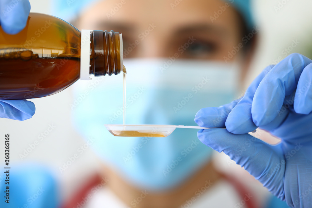 Nurse pouring medicated cold syrup into plastic spoon. Treatment of ...