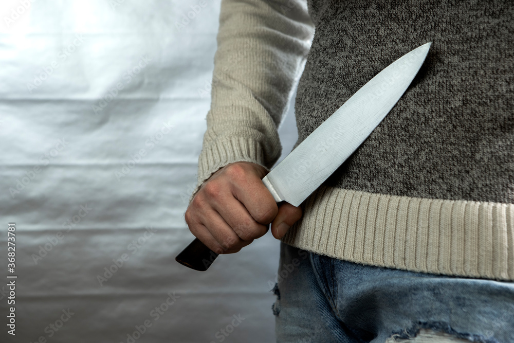 An evil man holds a shiny steel knife in his hand, a killer in action ...