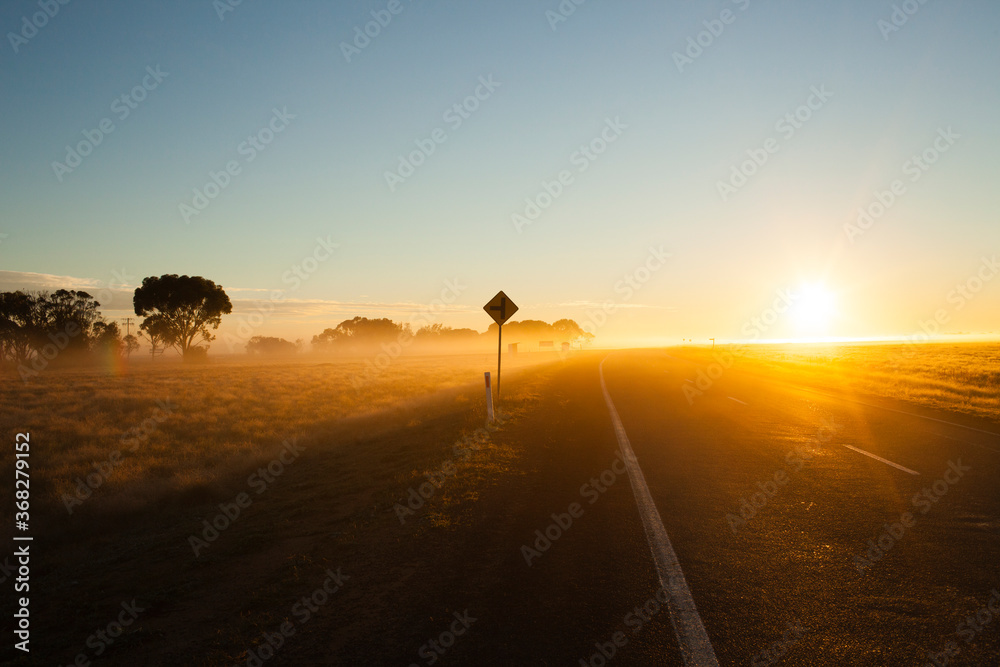 Sunrise on a regional highway with silhouette road side sign Stock ...