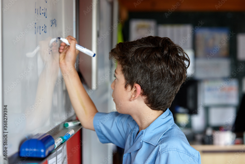 Primary school student in classroom writing on whiteboard Stock Photo ...