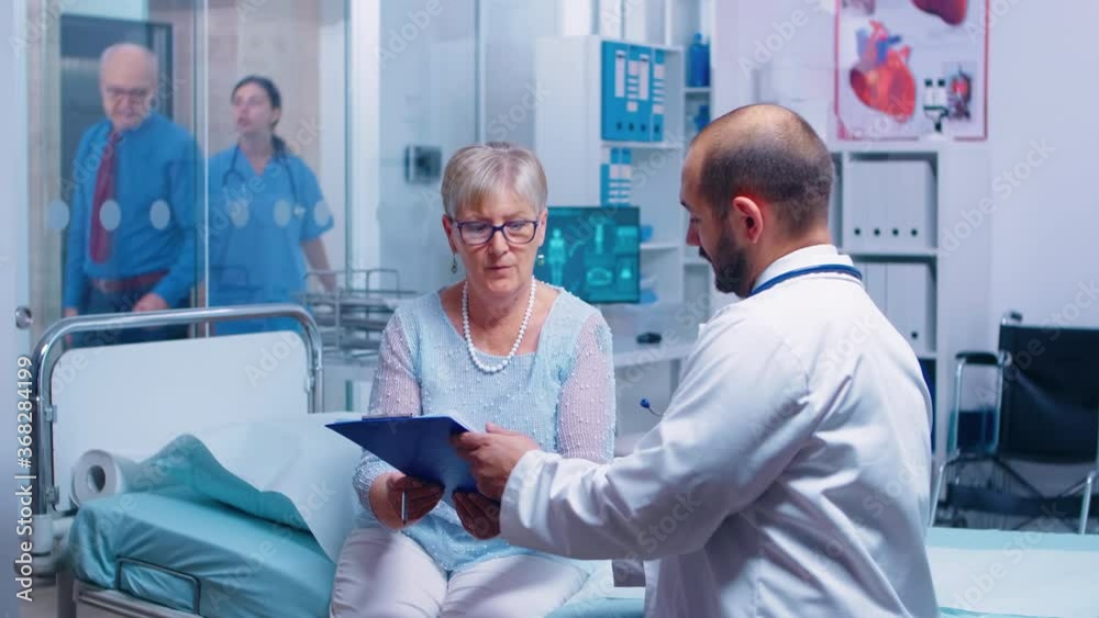 Senior patient signing medical decisions form sitting on hospital bed ...