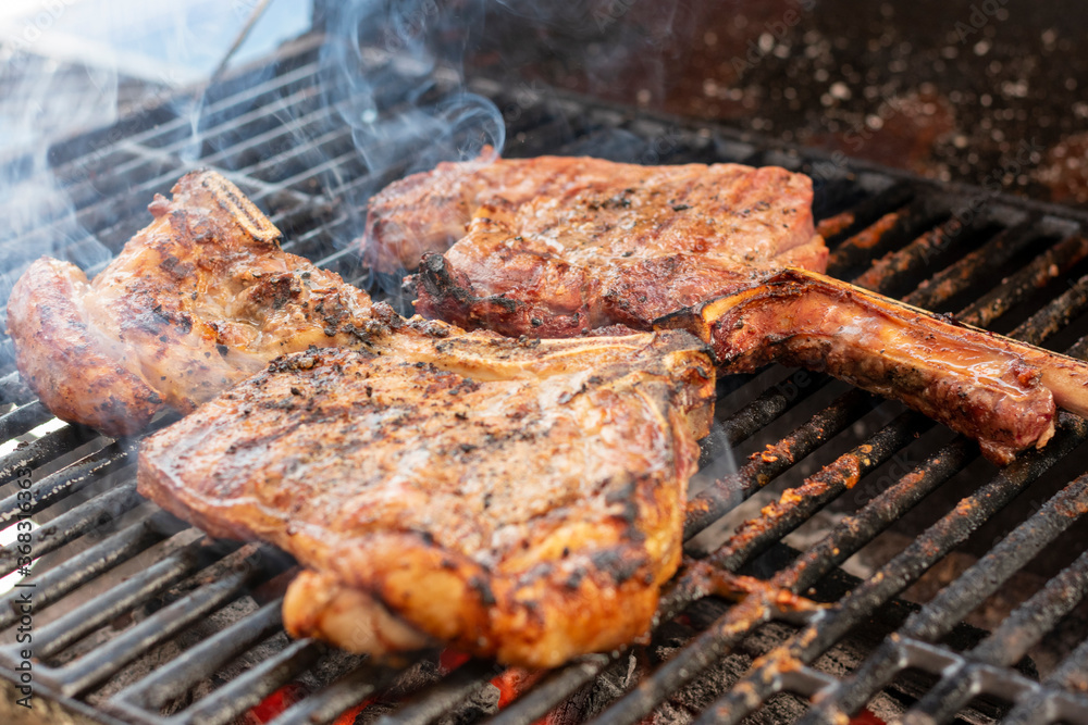 manos preparando distintos cortes en el asador y parrilla. tomahwk ...