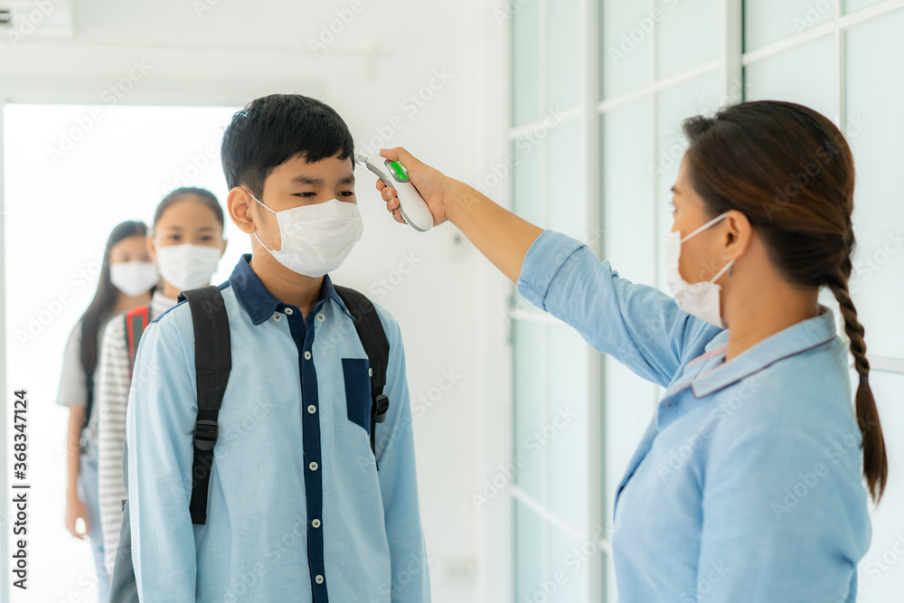 Asian woman teacher using thermometer temperature screening student for ...