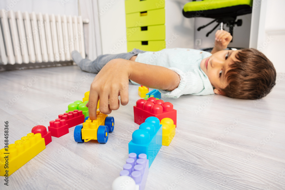 Special child, playing with blocks and cars laying on the floor focus ...