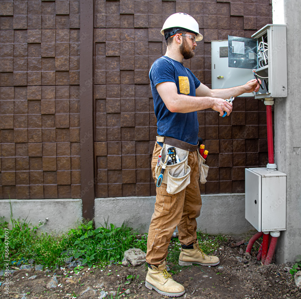 Electrician Builder at work, examines the cable connection in the ...