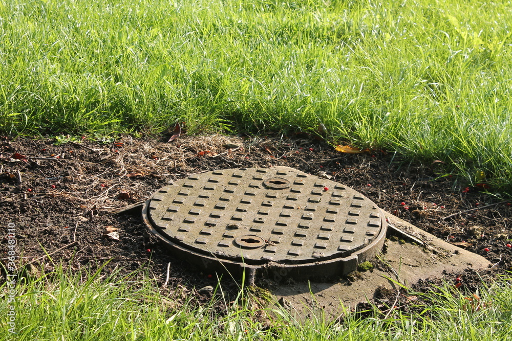 Round metal manhole cover surrounded by grass Stock Photo | Adobe Stock