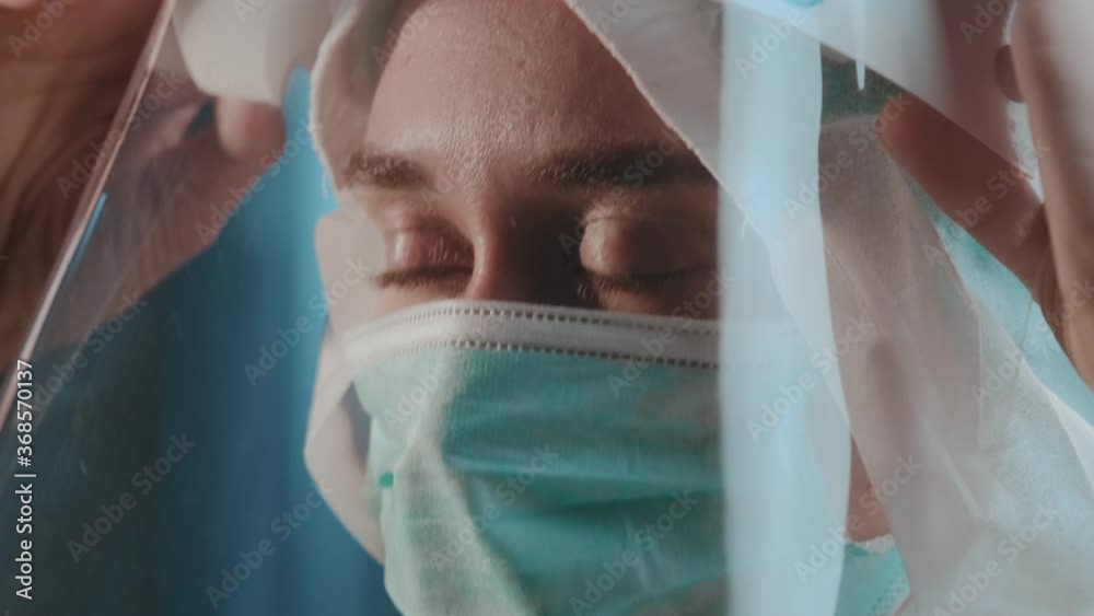 Close up of female doctor taking off medical protective PPE suit and ...