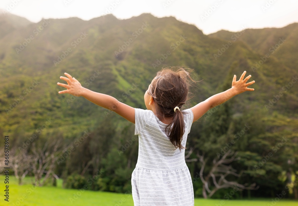 Happy people in nature. Little girl standing outside, arms raised ...