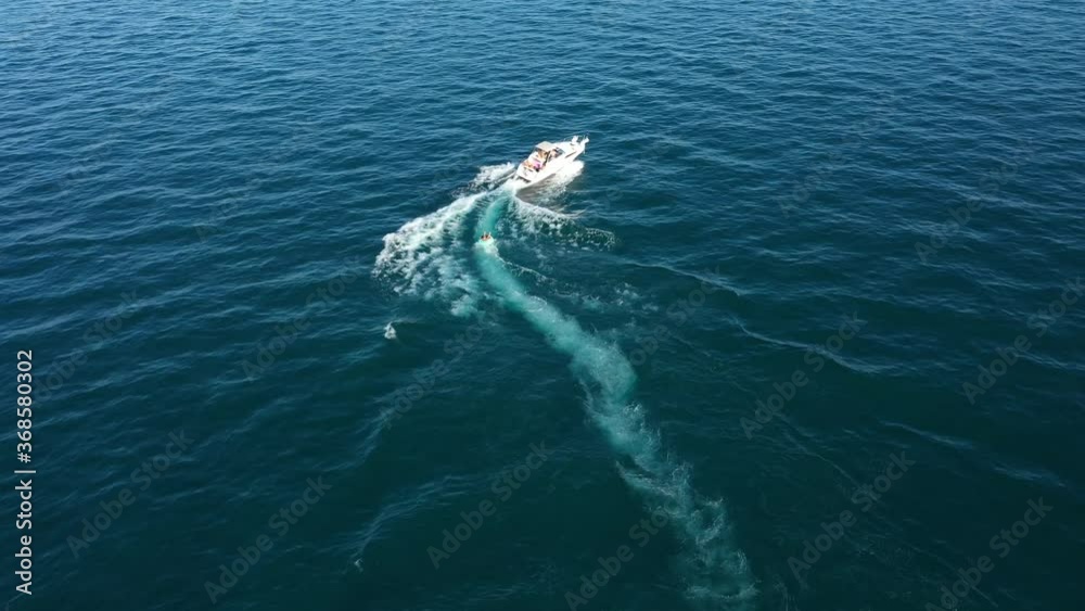 Aerial view of motor speed boat pulls Green inflatable rubber raft with ...