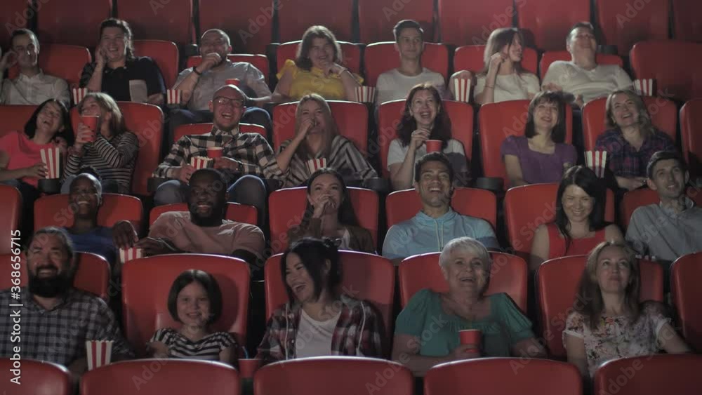 Joyful multi-ethnic spectators laughing while watching comedy movie in ...
