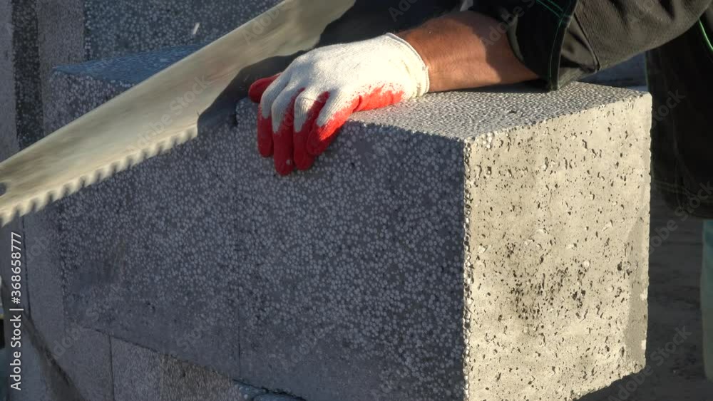 sawing a foam concrete block with a hand saw. The blocks are made of ...