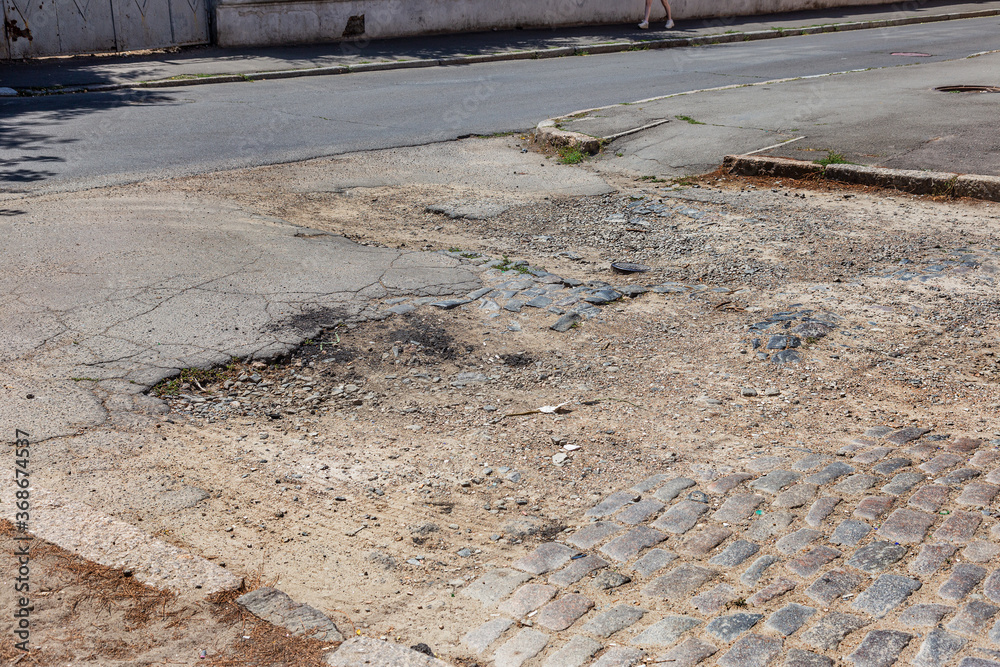 The damaged asphalt road with potholes caused by freeze-thaw cycles ...