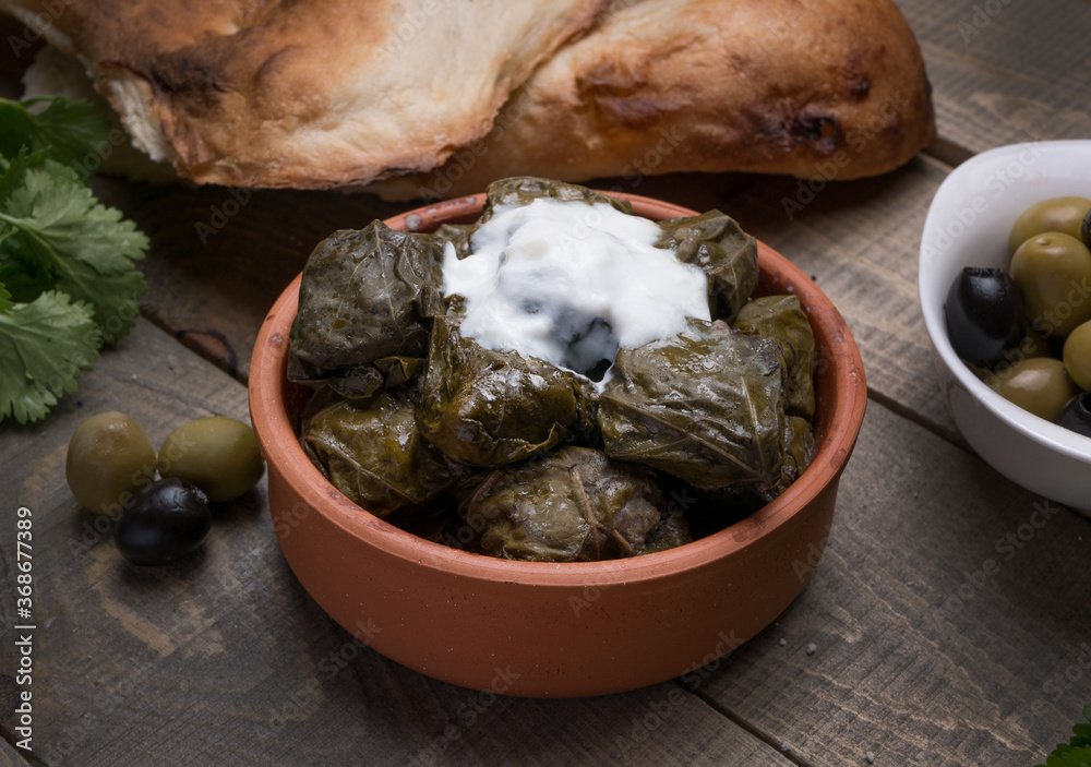 Traditional azerbaijan dolma in grape leaves on rustic wooden table ...