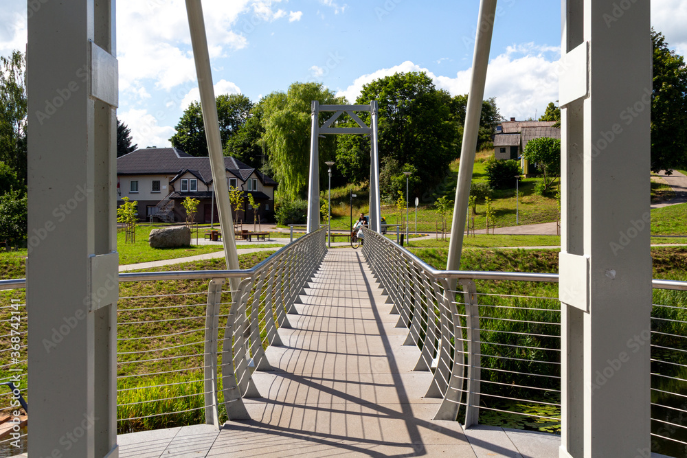 White footbridge over the river in the park. Walk outdoors. Metal ...