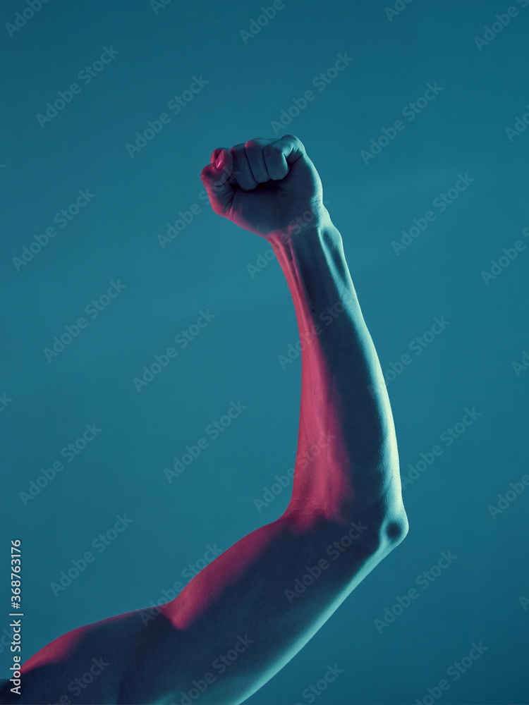 Male raised up hand in fist isolated on neon blue light background ...