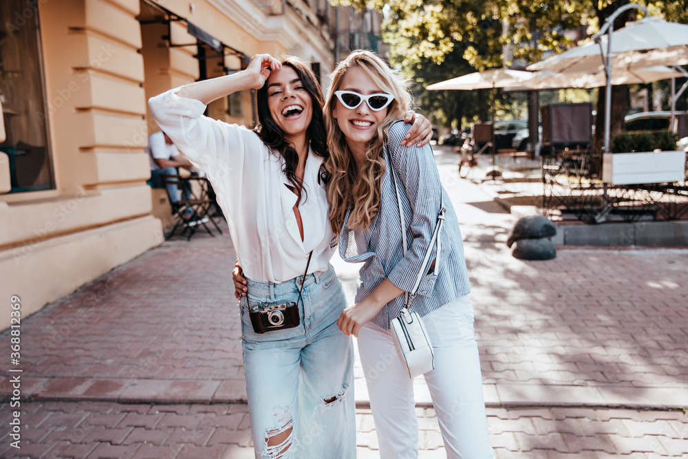 Dreamy caucasian girls posing together on the street. Pleased female ...