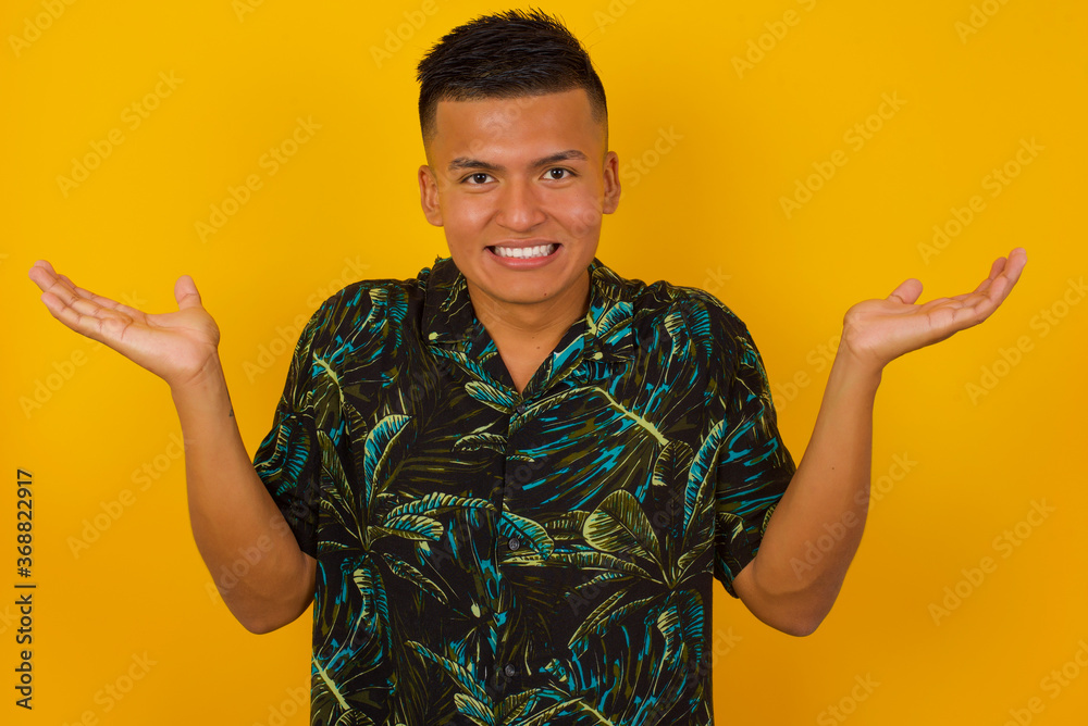 Puzzled and clueless young man with arms out, shrugging his shoulders ...