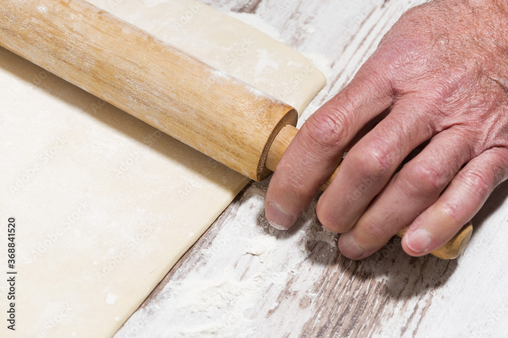 the process of rolling dough. man's hands and rolling pin, top view ...